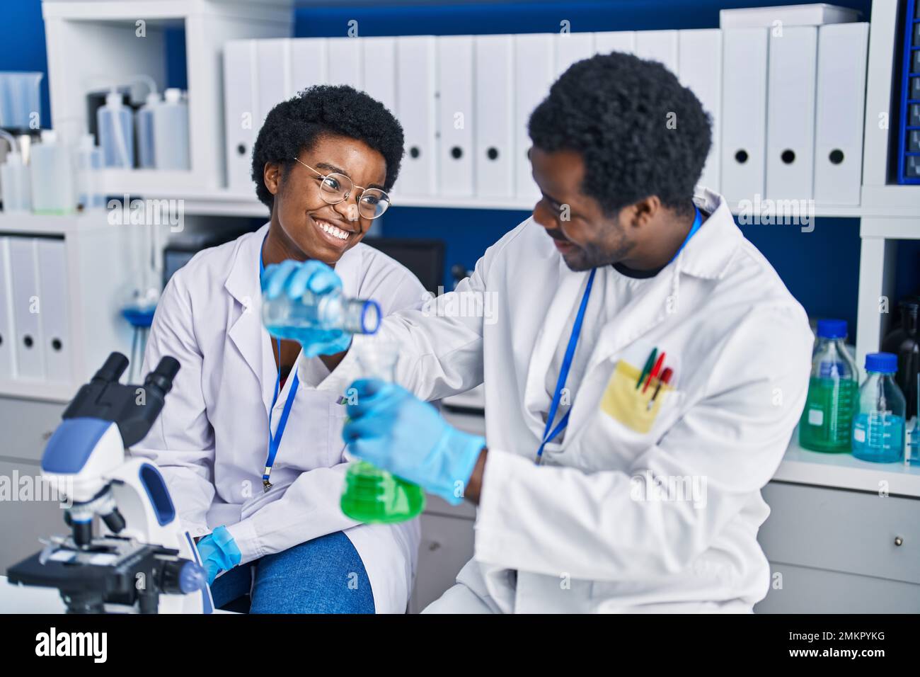 African american man and woman scientists measuring liquid at ...