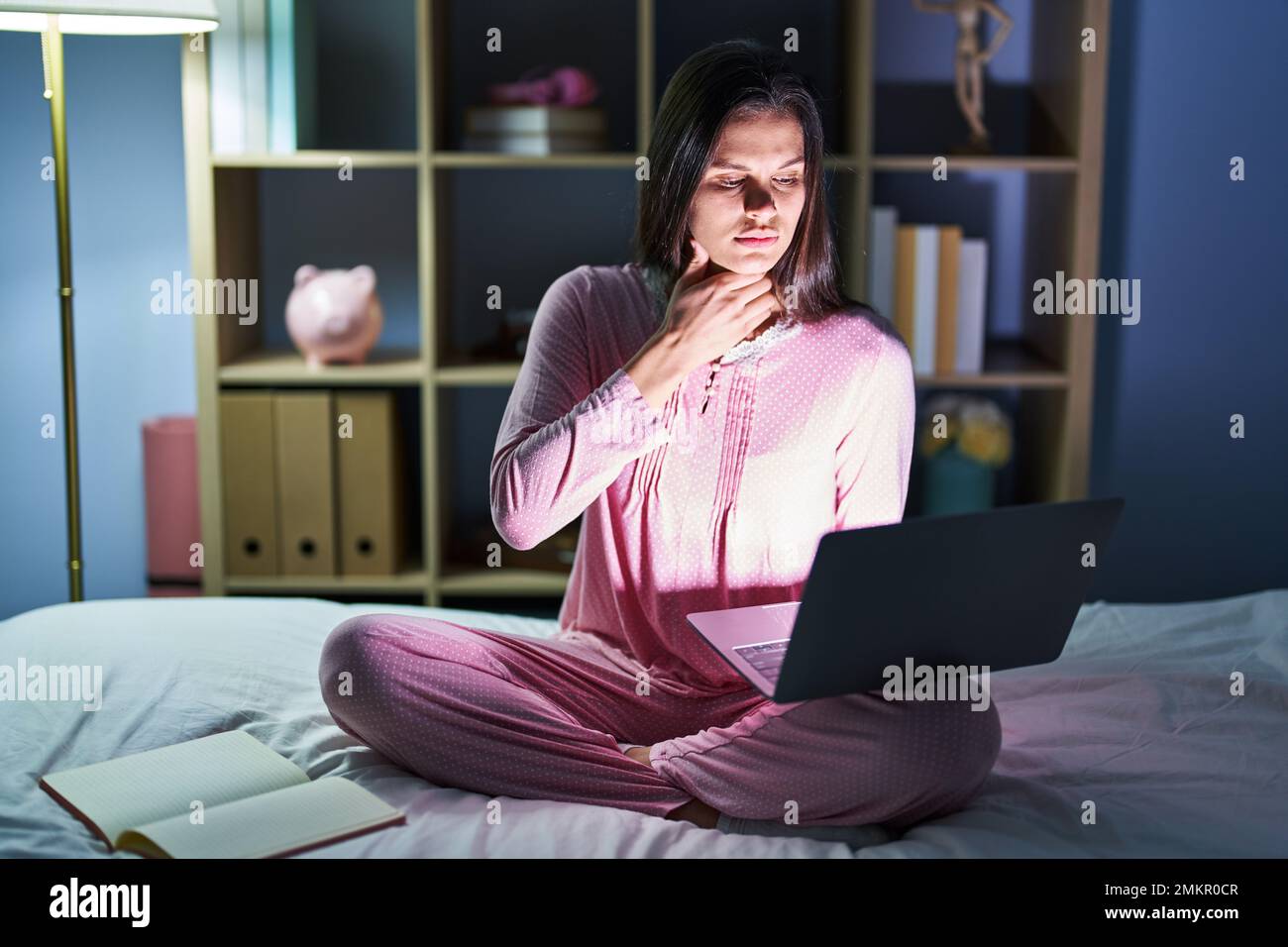 Young hispanic woman using computer laptop on the bed cutting throat ...