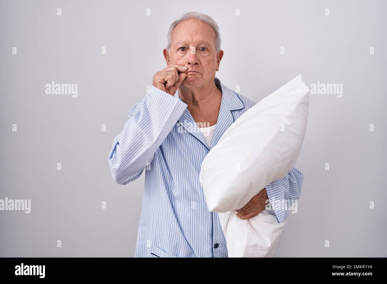 Senior man with grey hair wearing pijama hugging pillow mouth and lips ...
