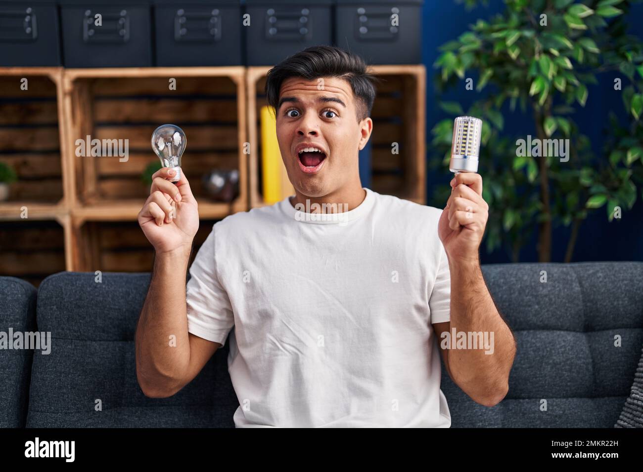 Hispanic man holding led lightbulb and incandescent bulb celebrating ...
