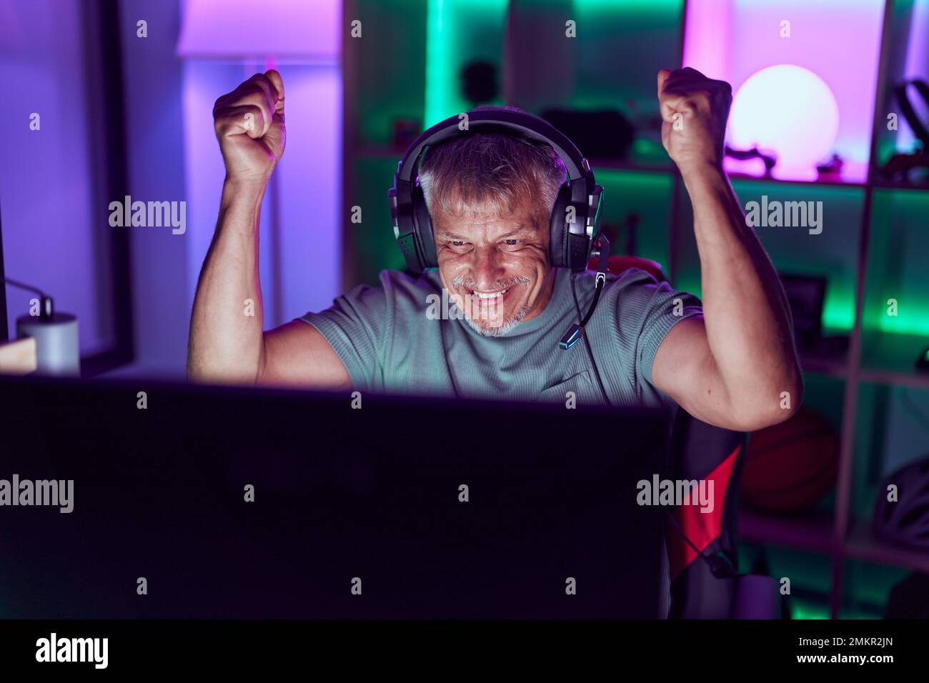 Middle age grey-haired man streamer playing video game using computer ...