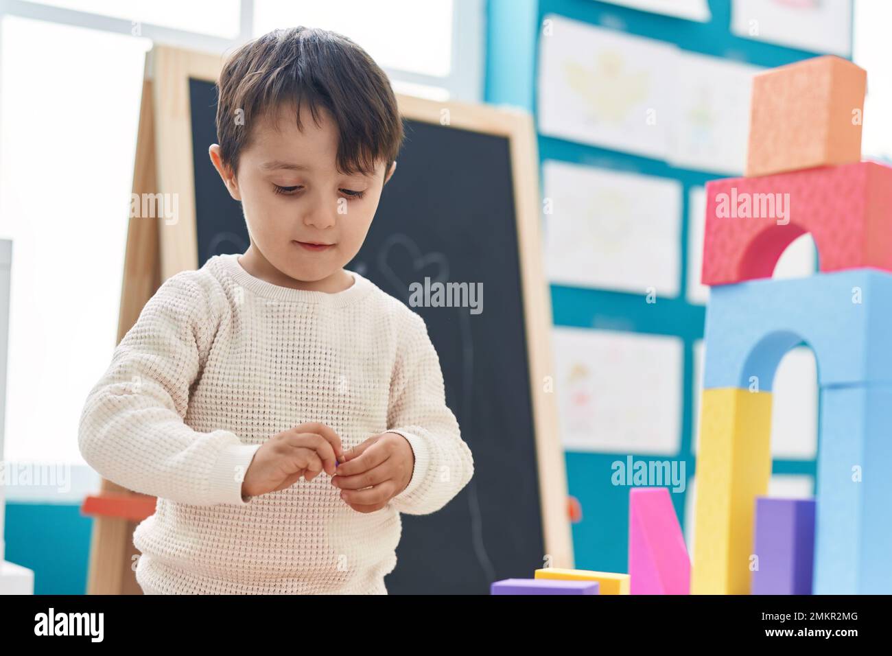 Adorable hispanic boy playing with construction blocks standing at ...