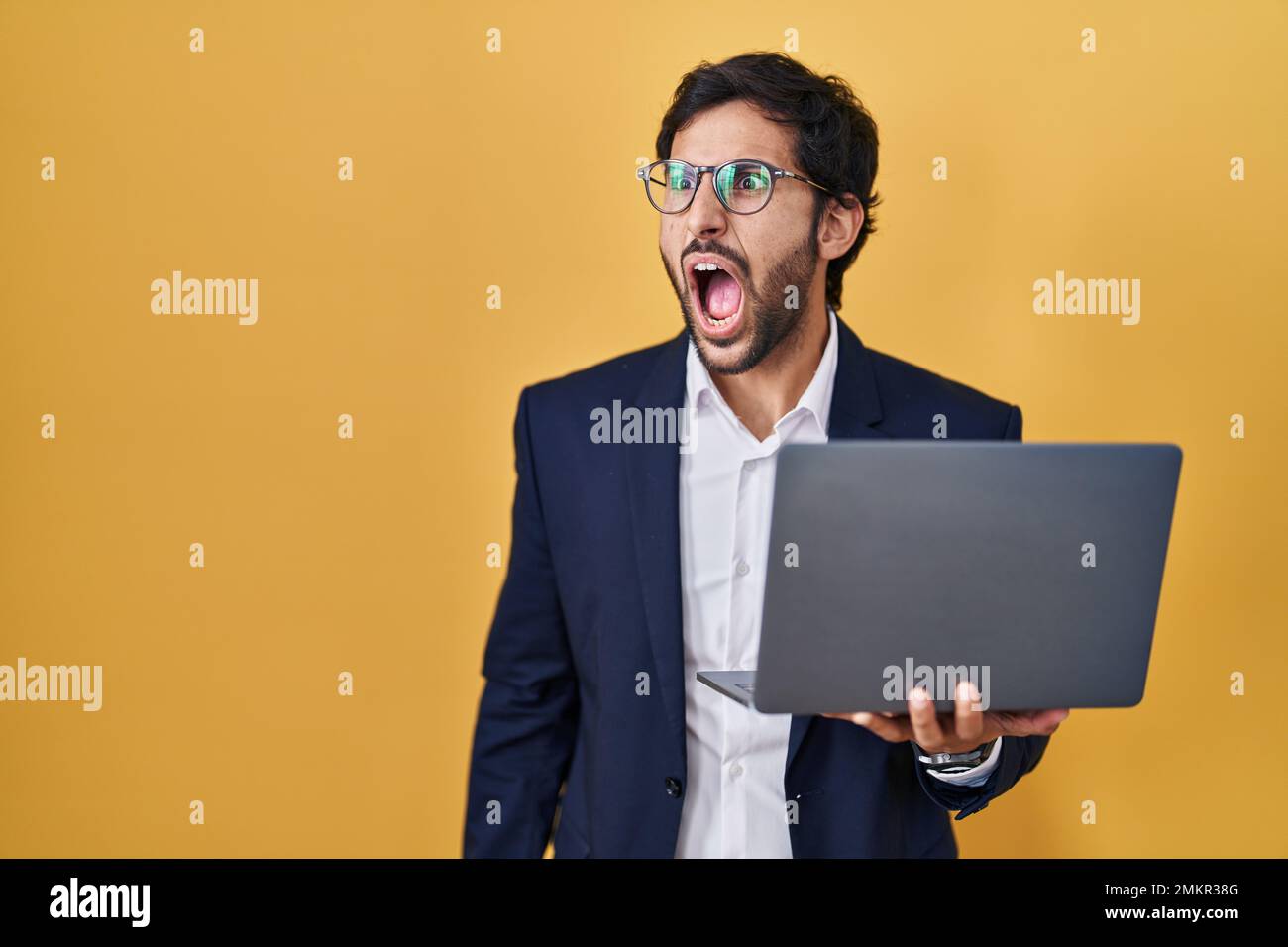 Handsome latin man working using computer laptop angry and mad ...