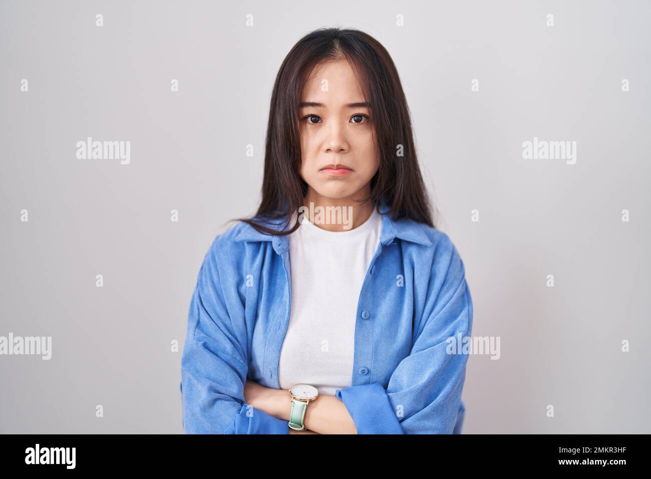 Young chinese woman standing over white background depressed and worry ...