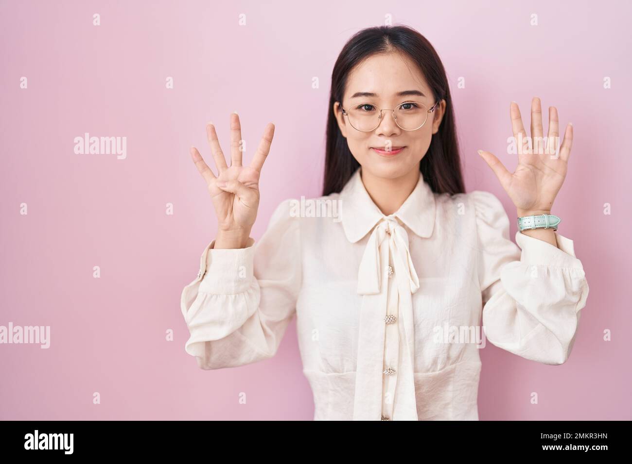 Young chinese woman standing over pink background showing and pointing ...