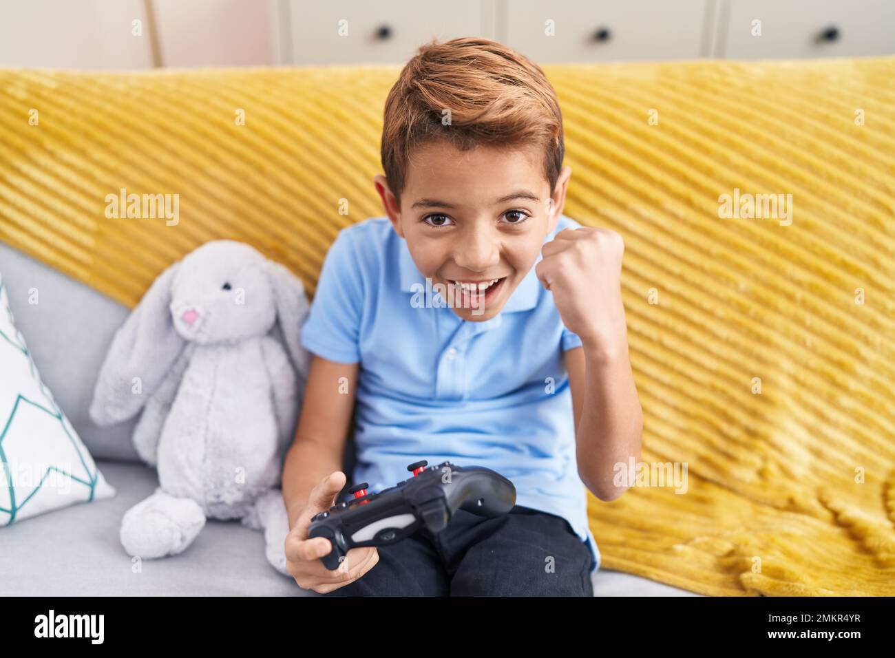 Adorable hispanic boy playing video game sitting on sofa at home Stock ...