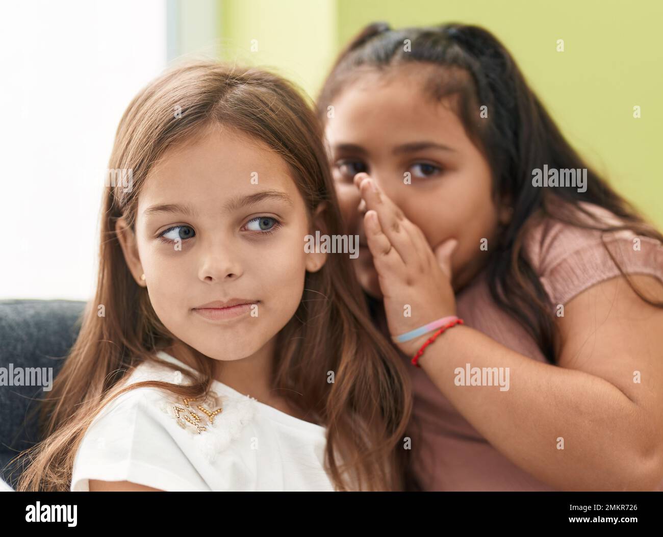 Two kids telling secret sitting on sofa at home Stock Photo - Alamy