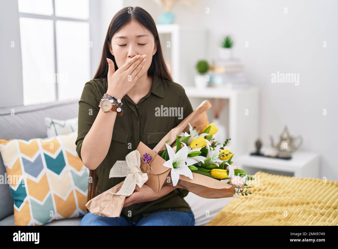 Chinese young woman holding bouquet of white flowers bored yawning ...
