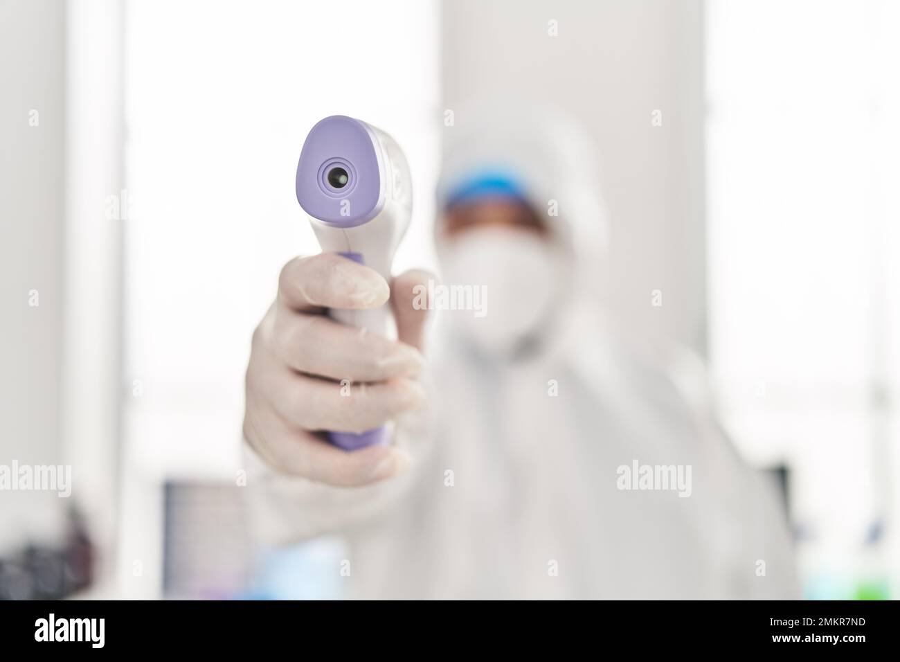Young latin man scientist wearing covid protection uniform holding ...