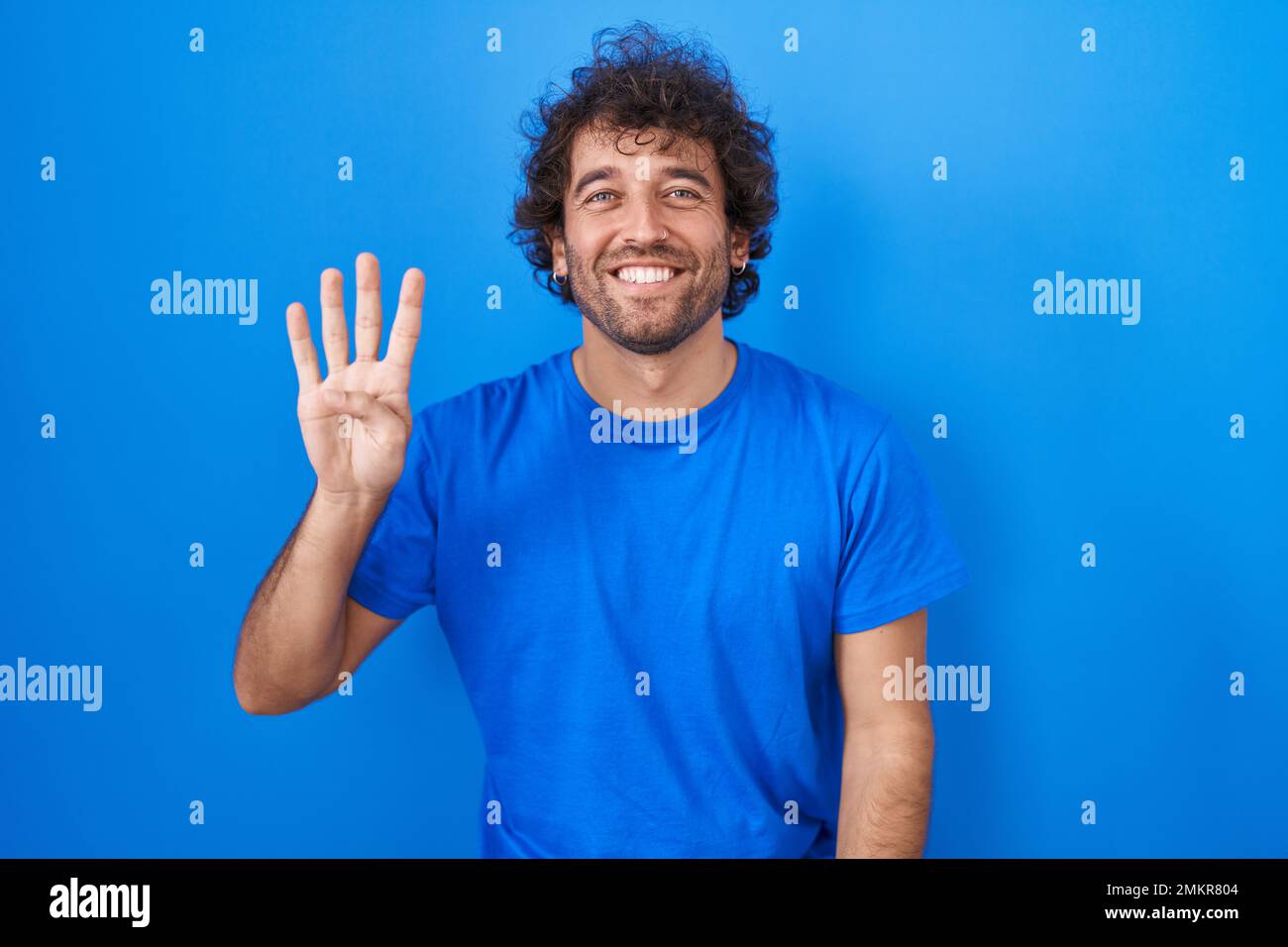 Hispanic young man standing over blue background showing and pointing ...
