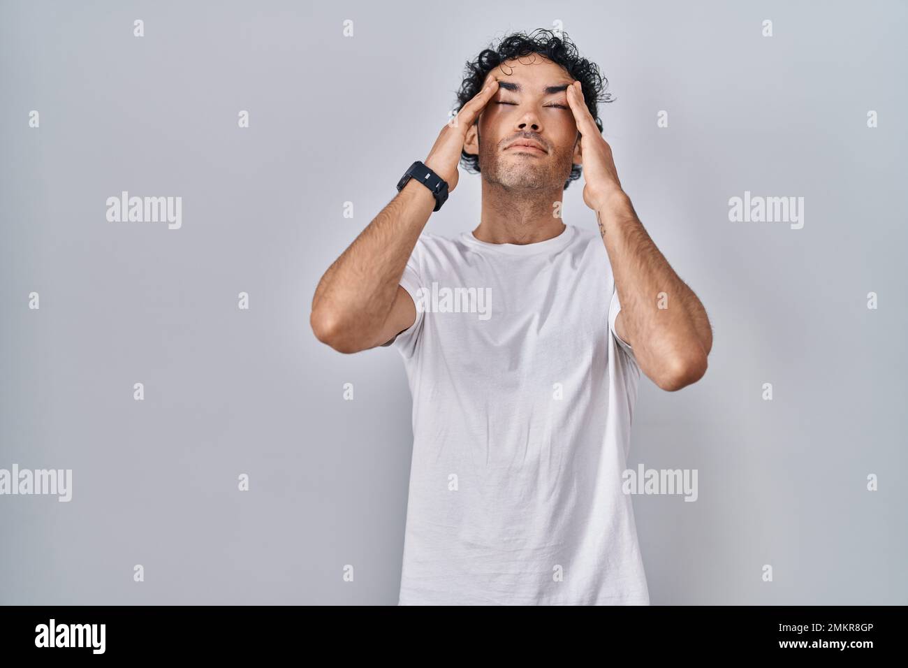 Hispanic man standing over isolated background trying to open eyes with ...