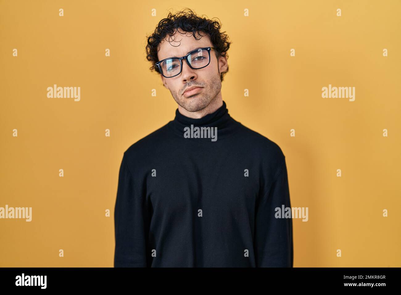 Hispanic man standing over yellow background looking sleepy and tired ...