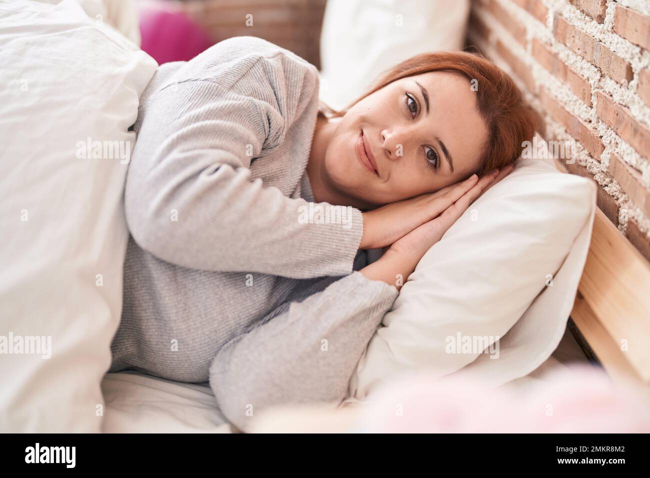 Young beautiful plus size woman smiling confident lying on bed at ...