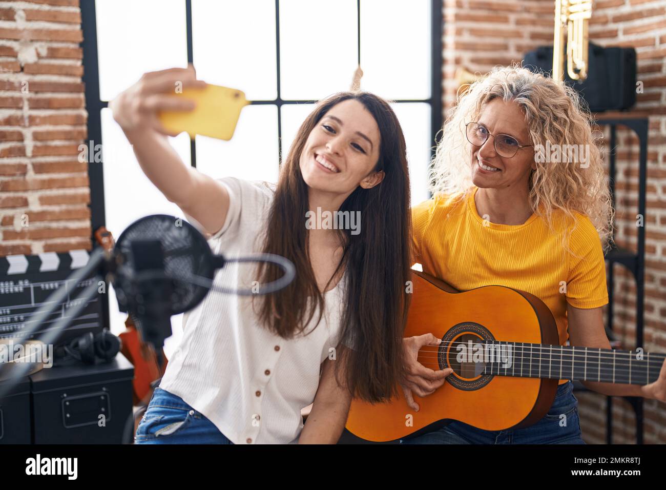 Two women musicians playing classical guitar making selfie by ...