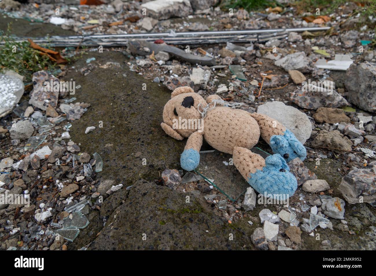 Toy (teddy bear) lies on the ground against the background of broken ...