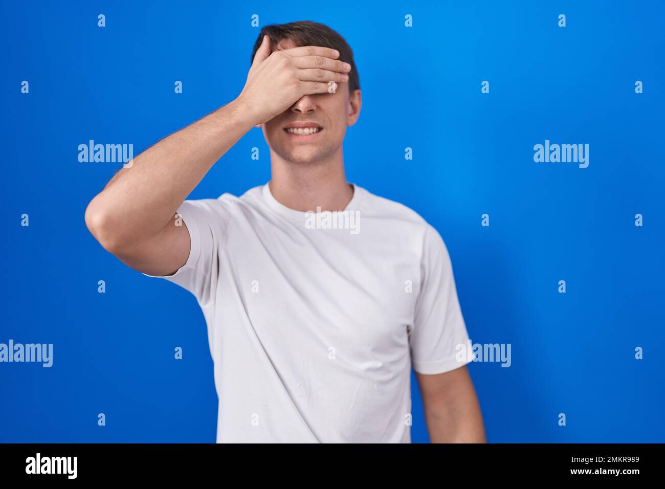 Caucasian blond man standing over blue background smiling and laughing ...