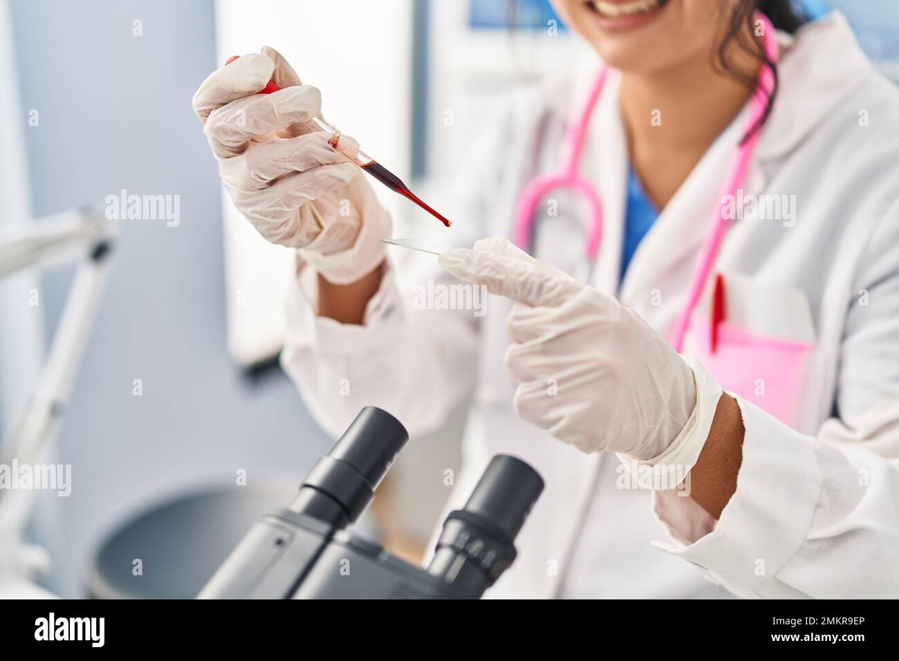 Young chinese woman wearing scientist uniform analysing blood at ...