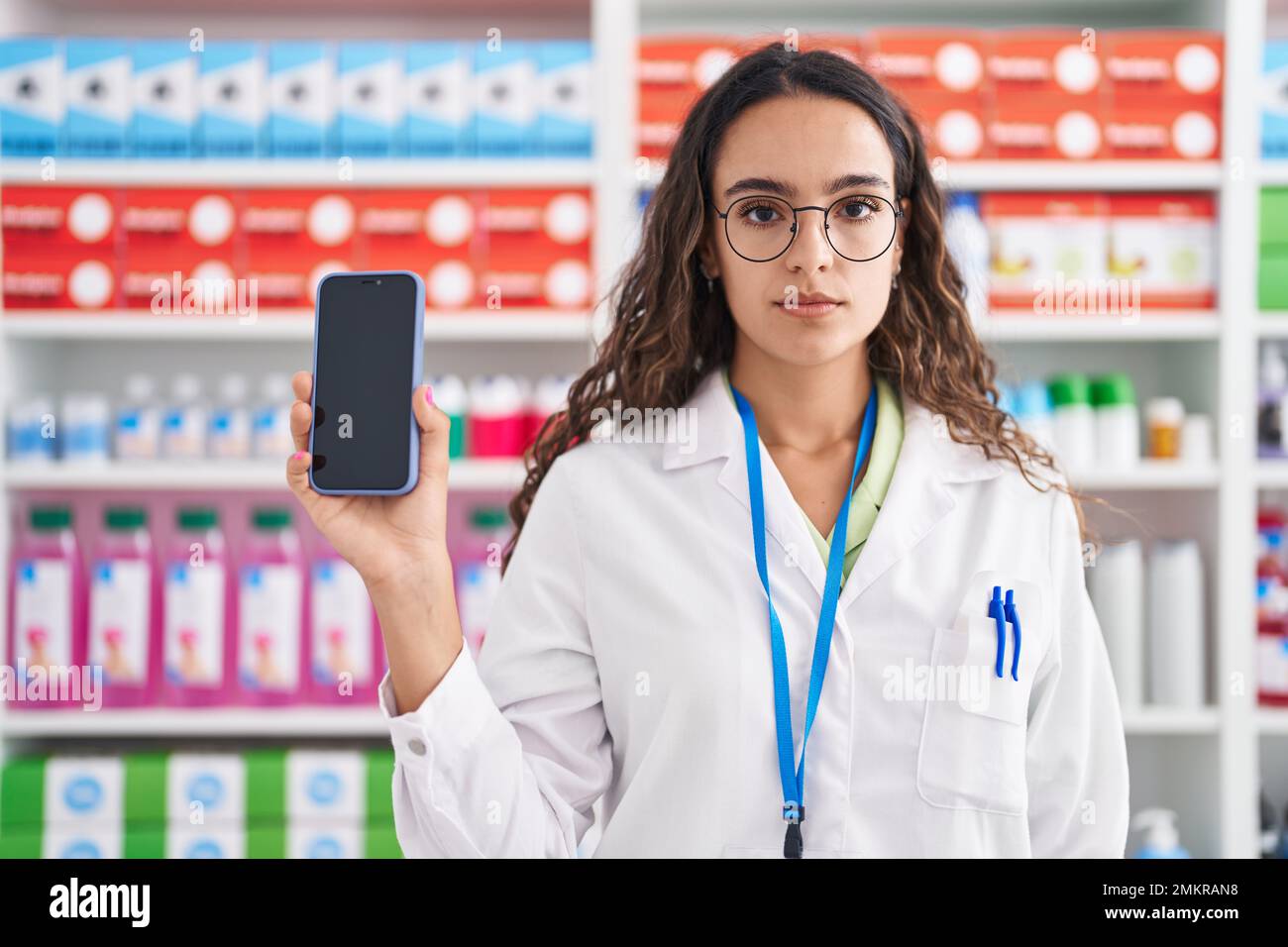 Young beautiful hispanic woman pharmacist showing smartphone app at ...
