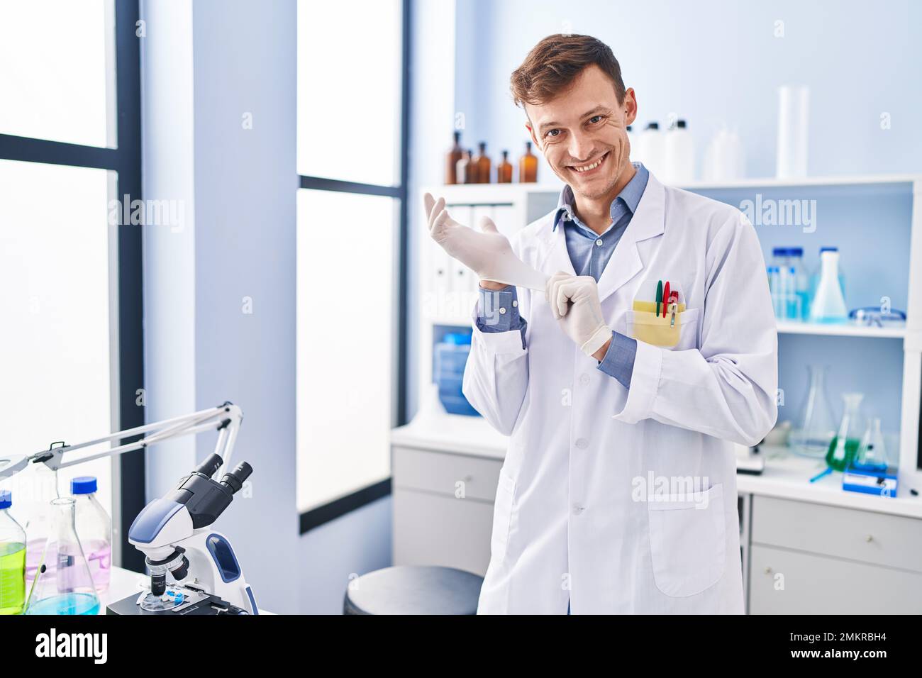 Young man scientist smiling confident wearing gloves at laboratory Stock Photo - Alamy