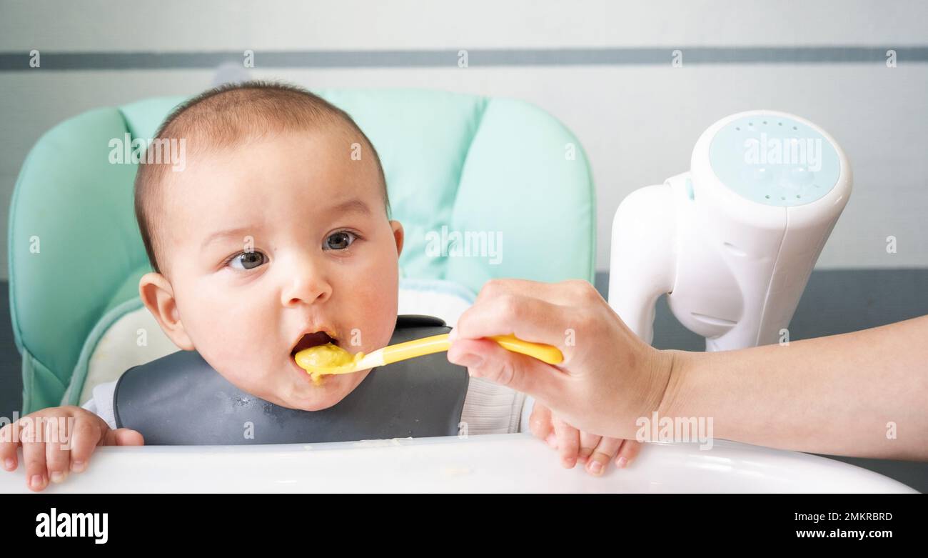 Mom feeds the baby with a spoon of vegetable puree at the children's ...