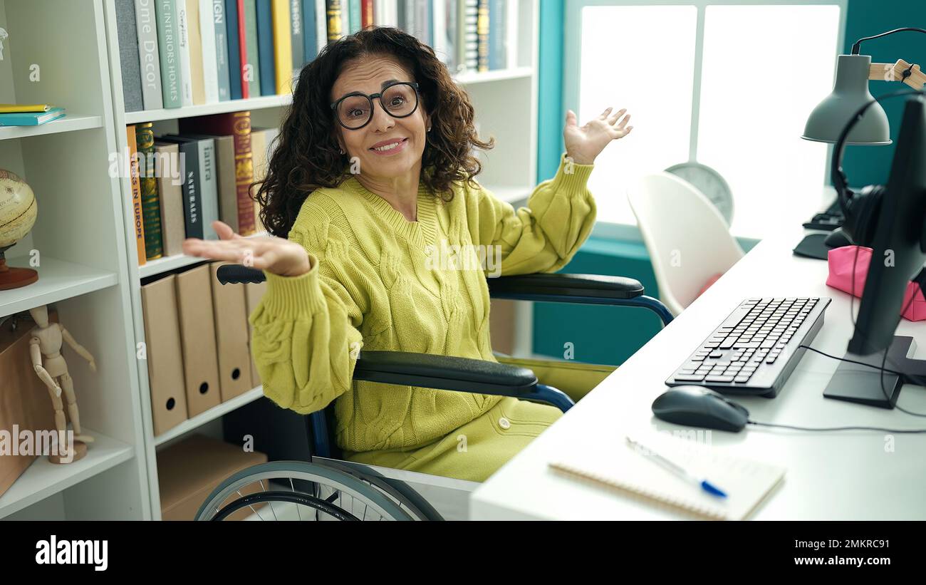 Middle age hispanic woman teacher sitting on wheelchair doing unsure ...