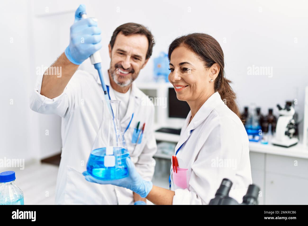 Middle age man and woman partners wearing scientist uniform using ...