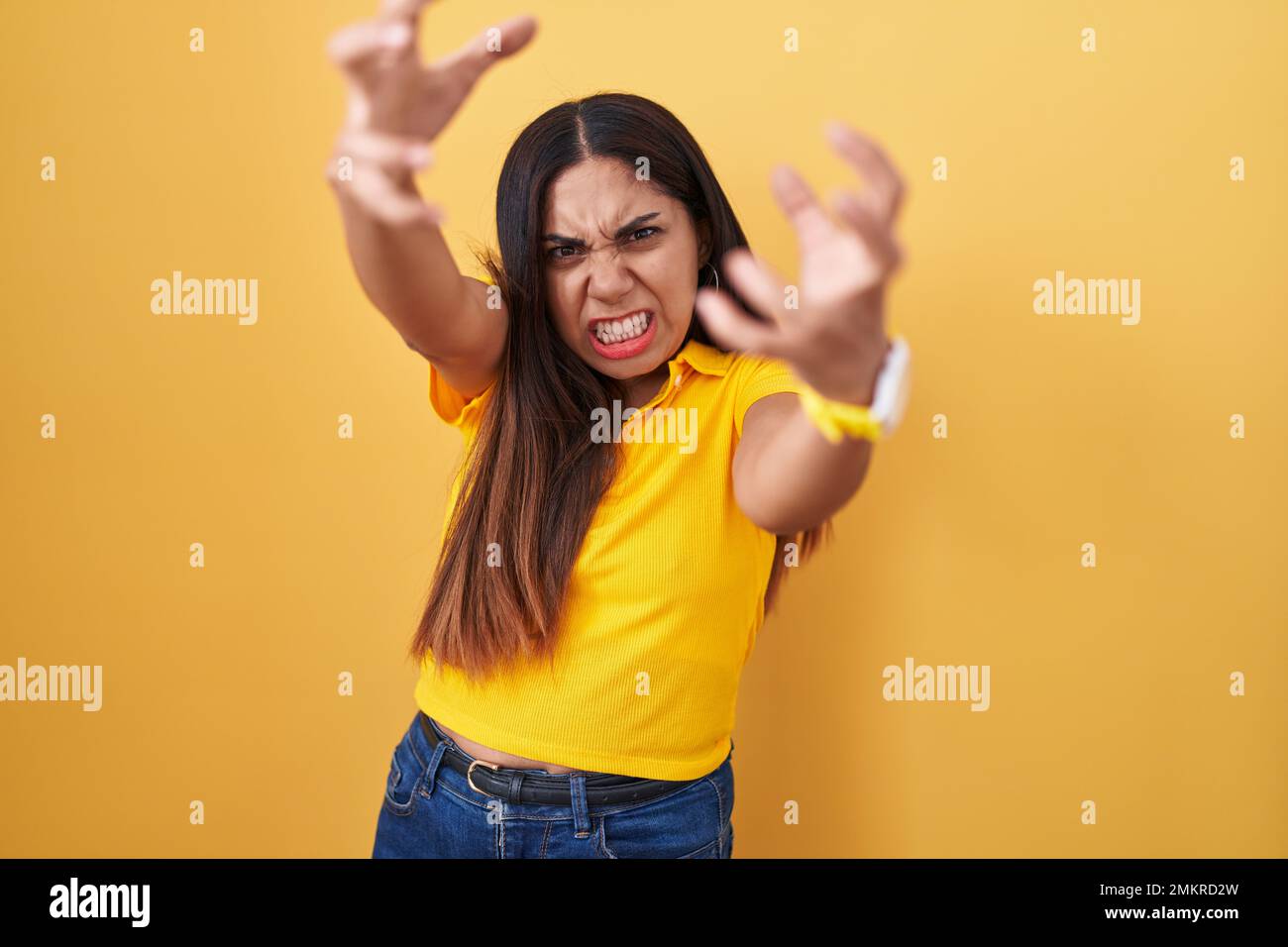 Young arab woman standing over yellow background shouting frustrated ...