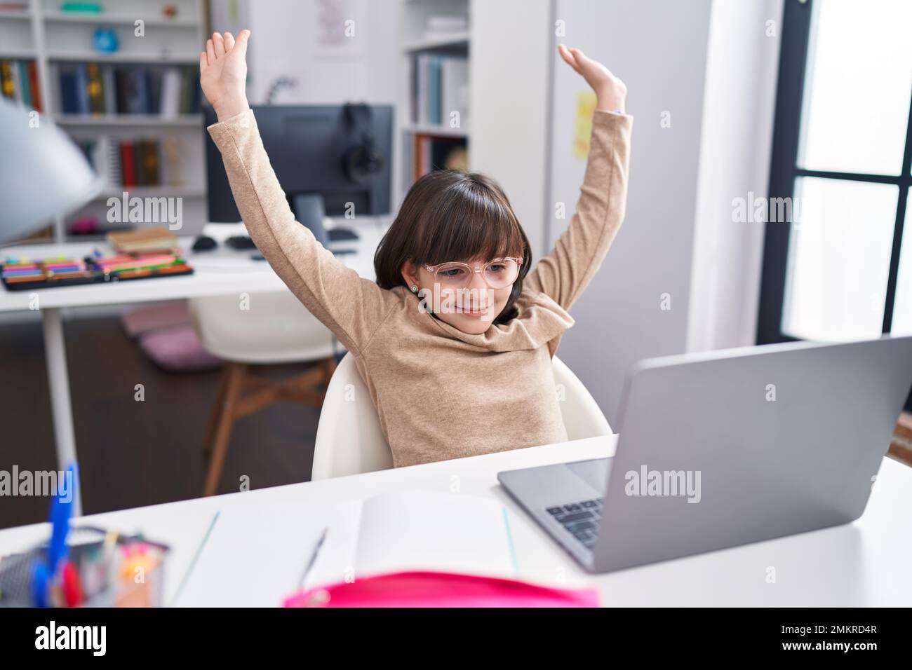 Adorable hispanic girl student using laptop with celebration expression ...