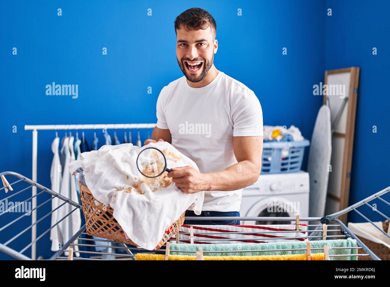 Handsome hispanic man holding magnifying glass looking for stain at ...