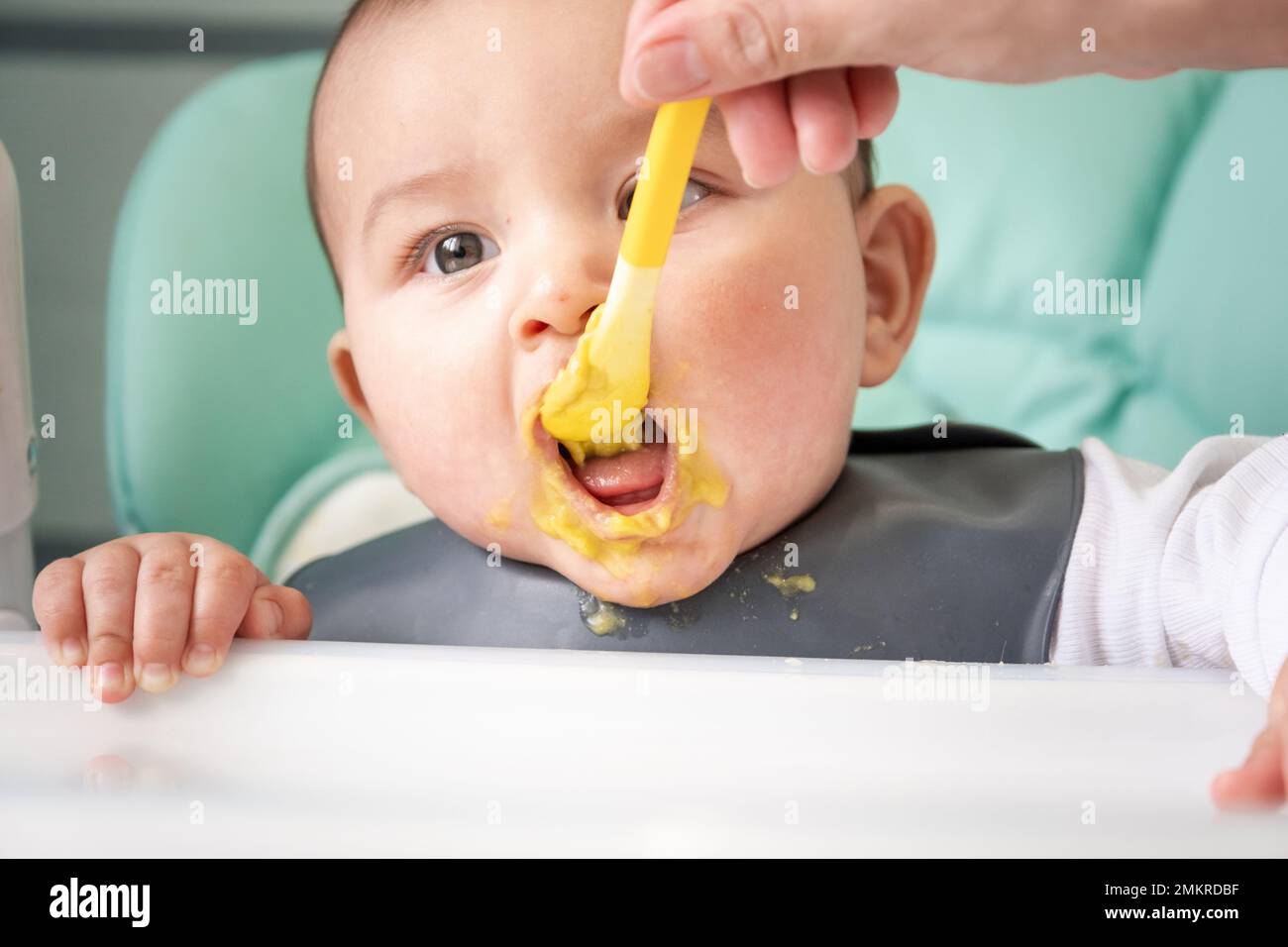 Mom feeds the baby with a spoon of vegetable puree at the children's ...