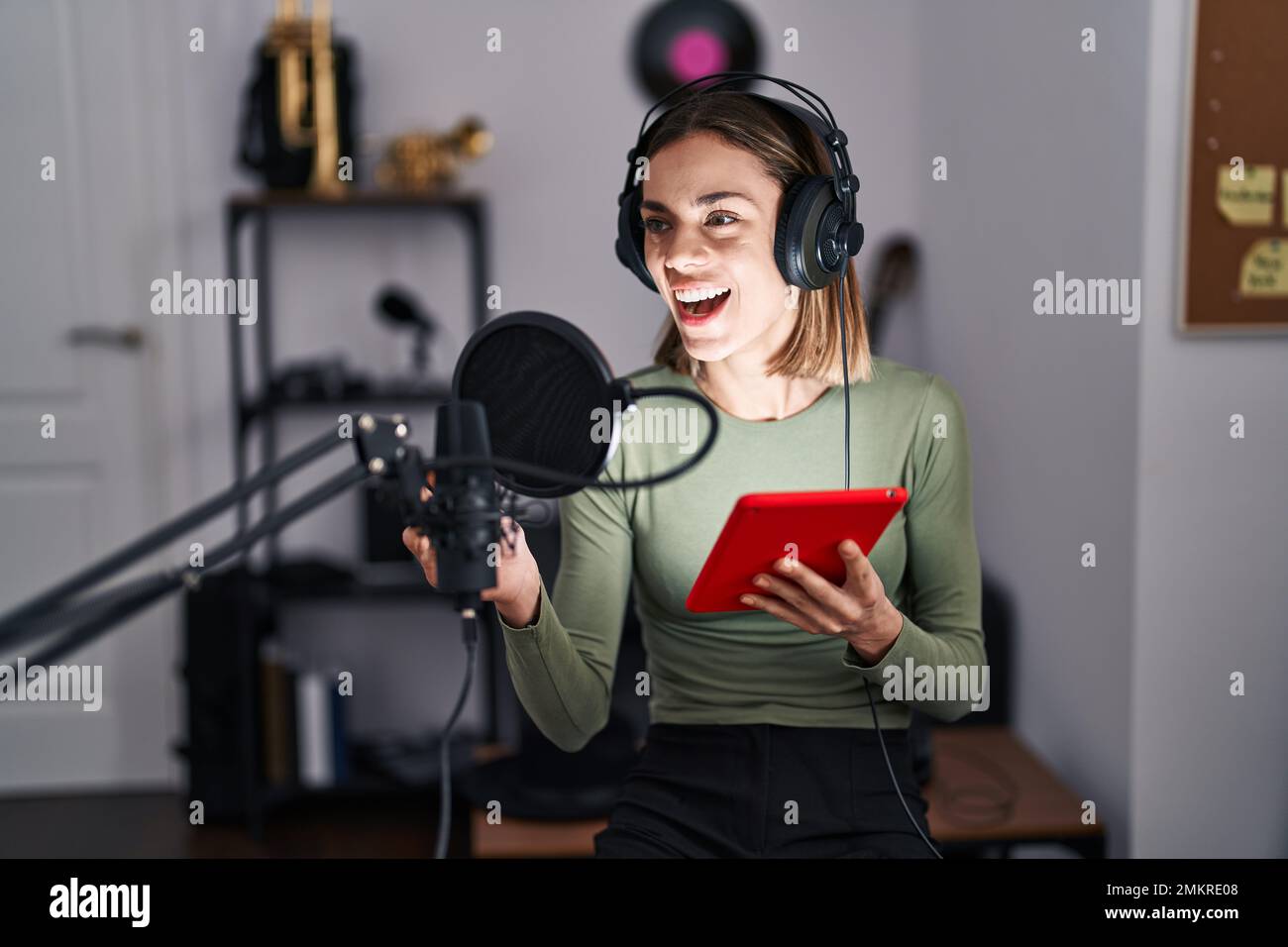 Hispanic woman singing song using microphone and tablet looking ...