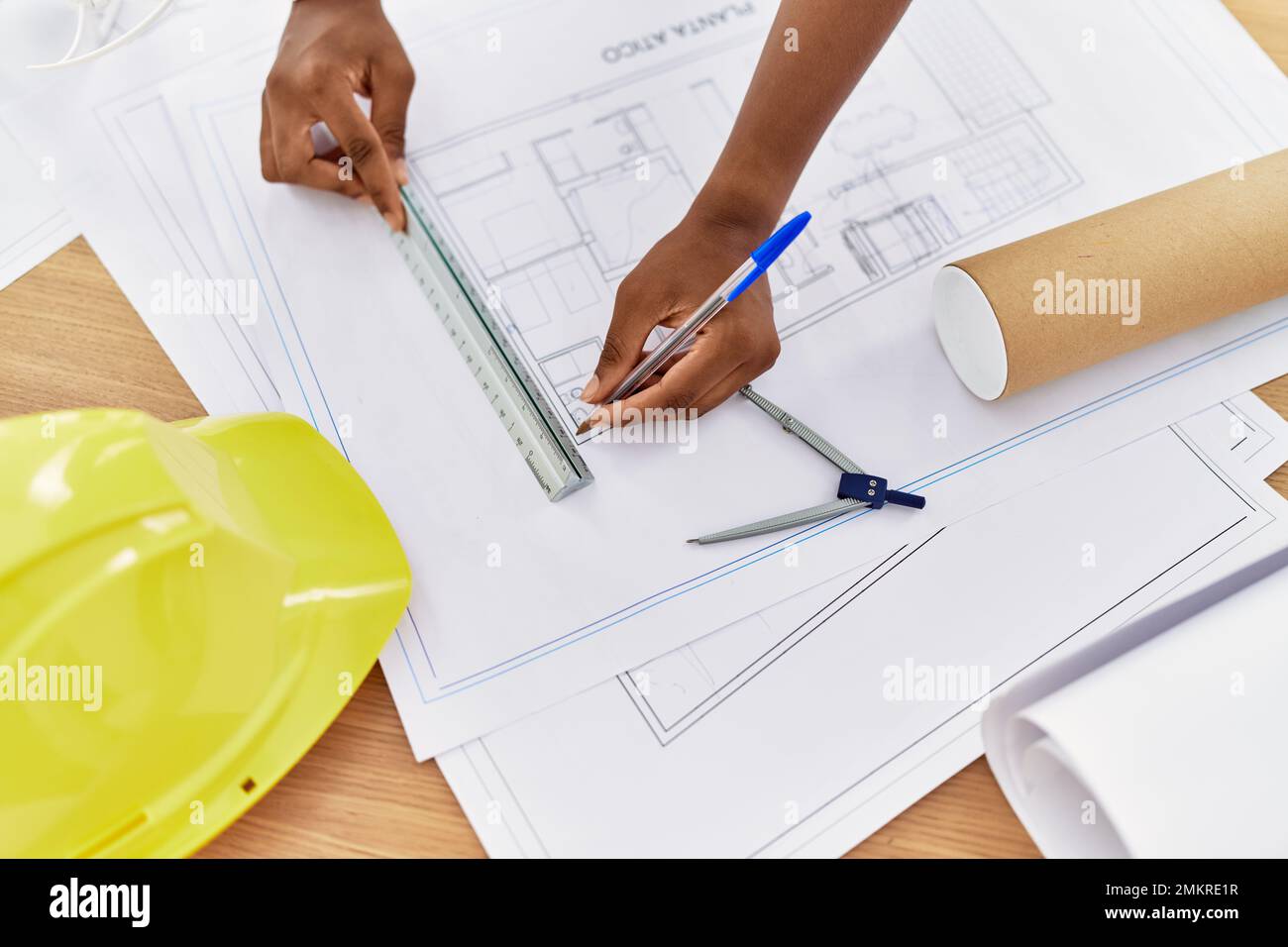 Young african american woman architect writing on house plans at ...