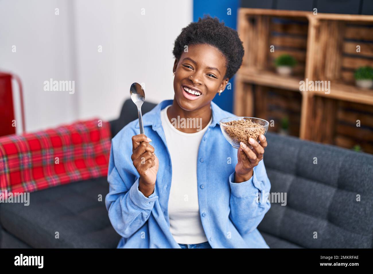 African american woman eating healthy whole grain cereals smiling and ...