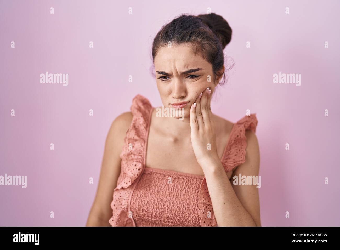Young teenager girl standing over pink background touching mouth with ...