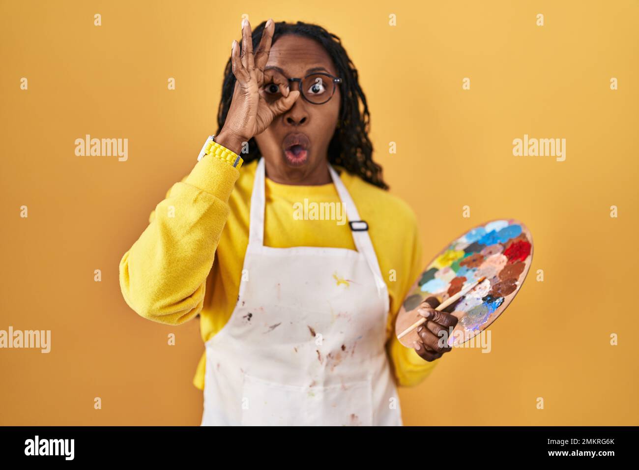 African woman holding painter palette doing ok gesture shocked with ...