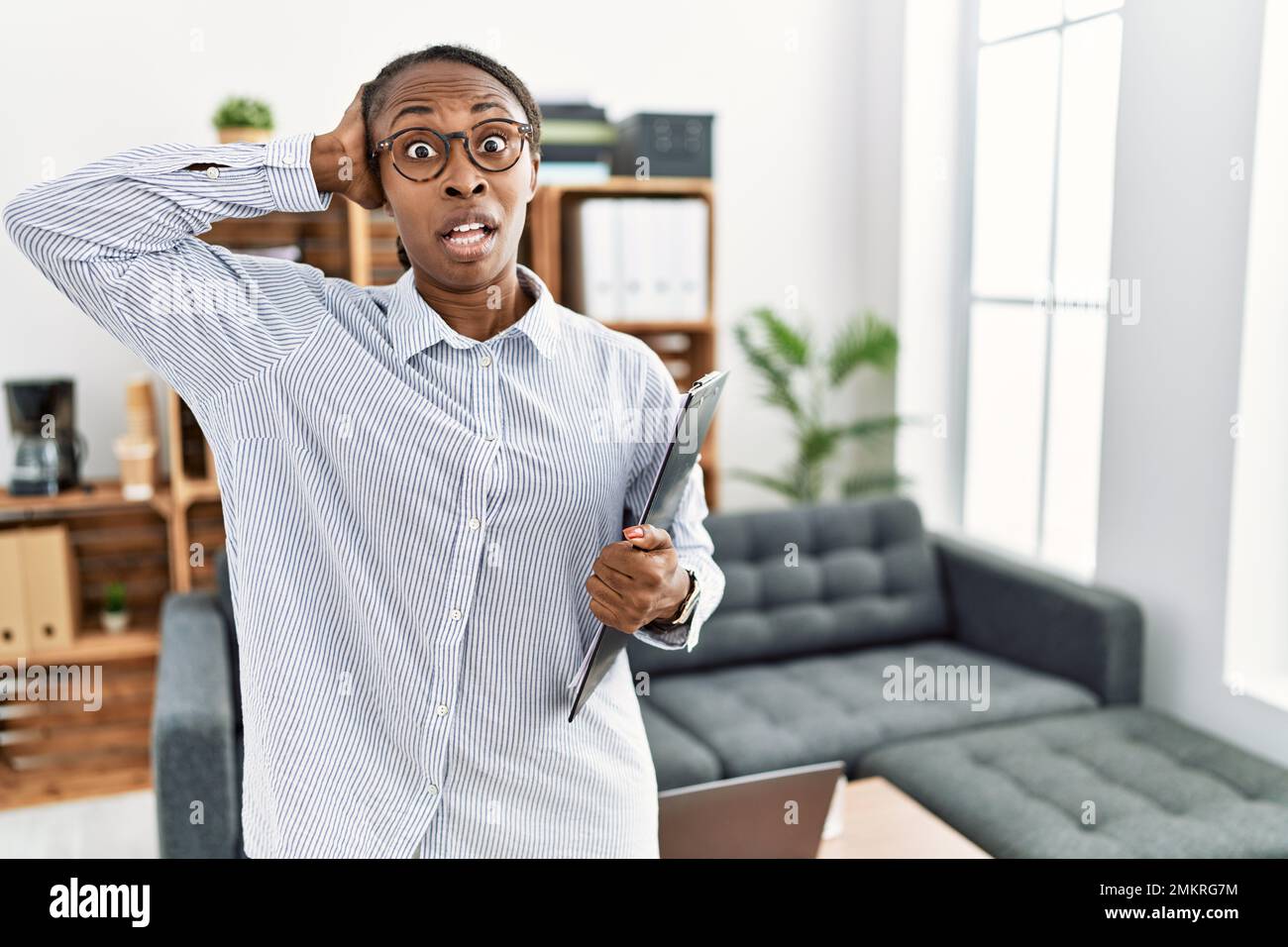 African woman working at psychology clinic crazy and scared with hands ...