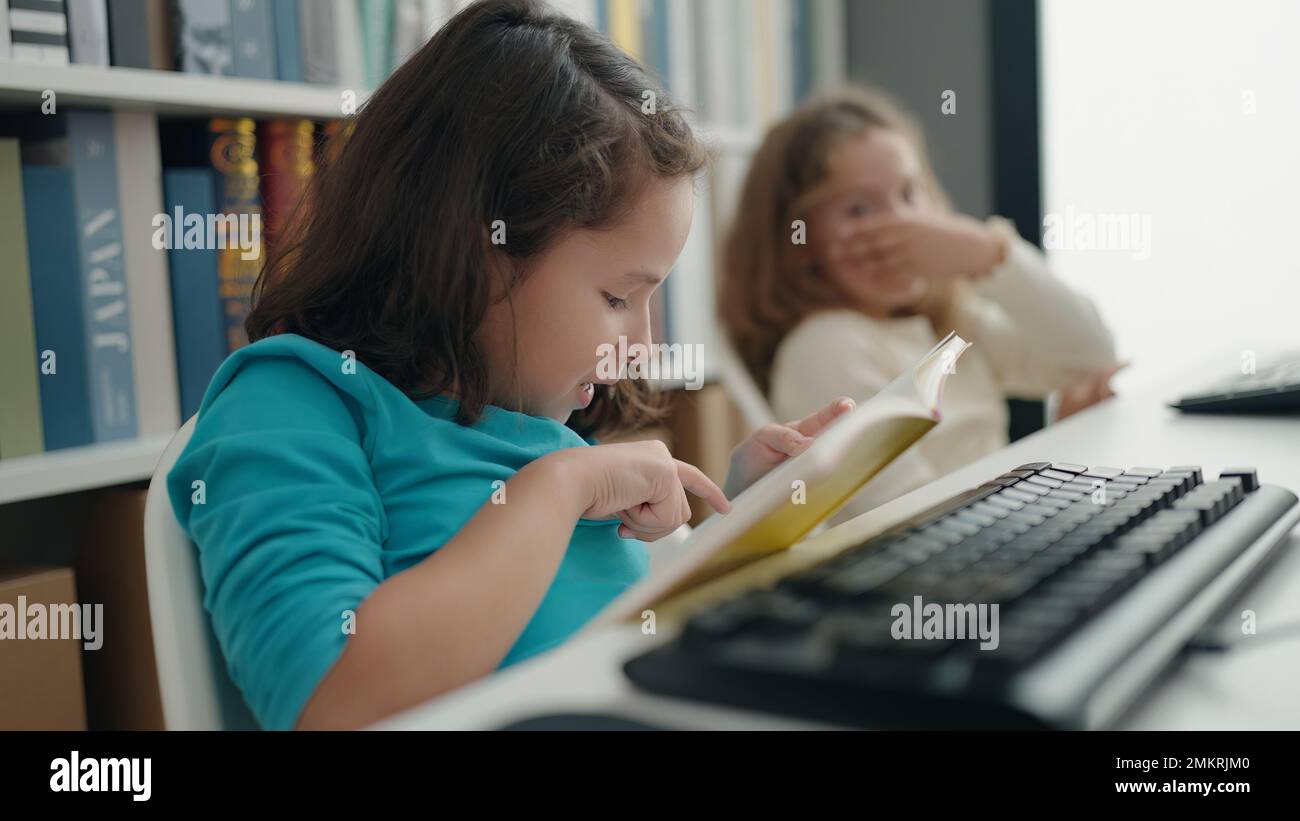 Two kids students using computer reading book at classroom Stock Photo ...