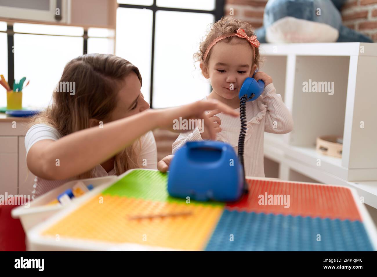 Teacher and toddler playing with telephone toy at kindergarten Stock ...