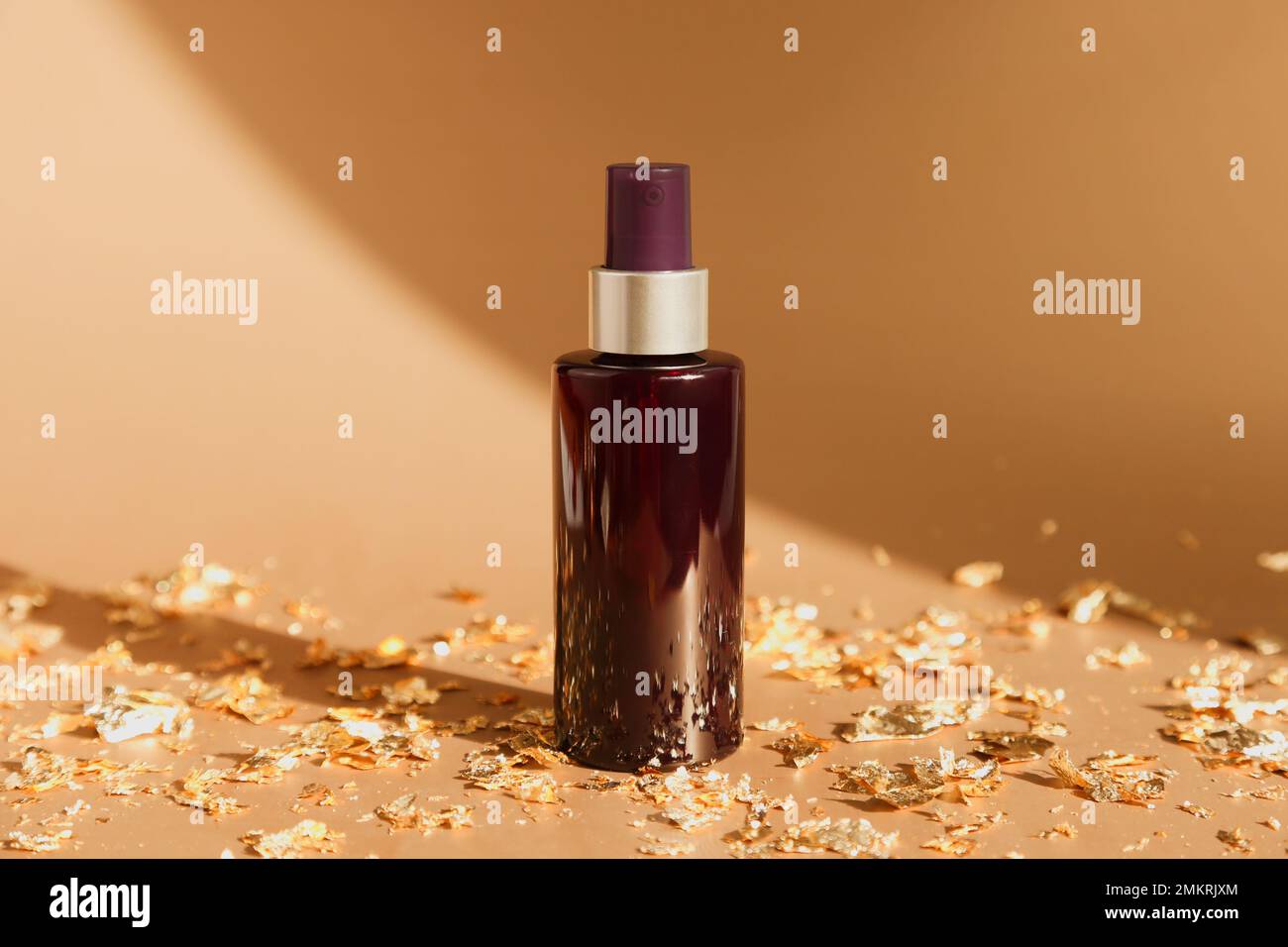 Unbranded brown spray bottle and pieces of gold paper on gold ...