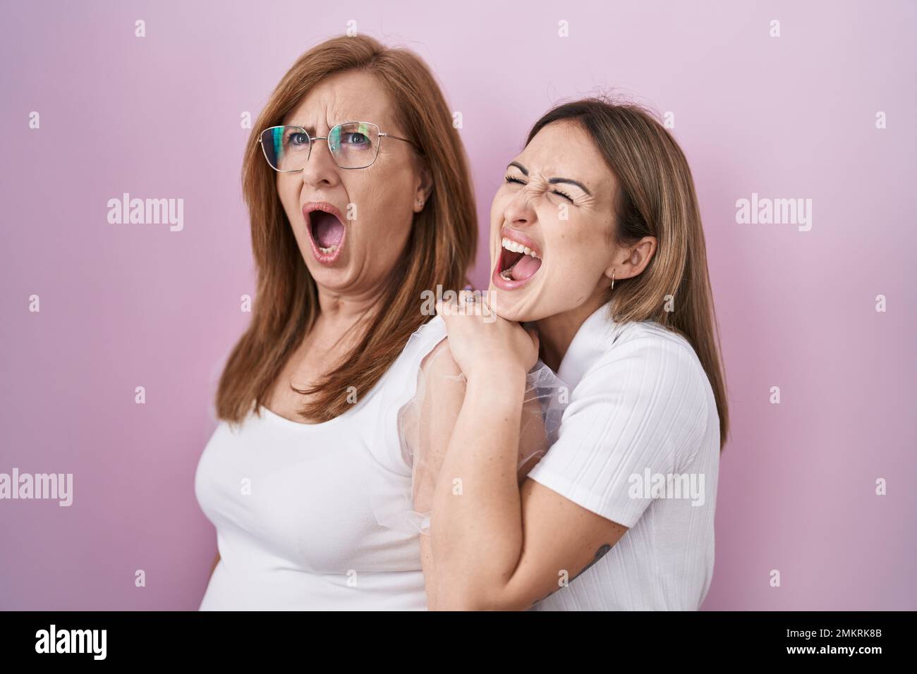 Hispanic mother and daughter wearing casual white t shirt angry and mad ...