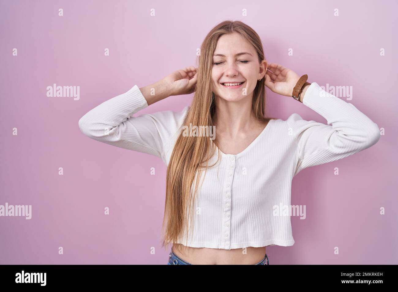 Young caucasian woman standing over pink background smiling pulling ...