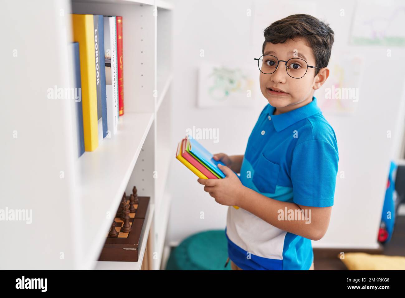 Adorable hispanic boy student smiling confident holding books of ...
