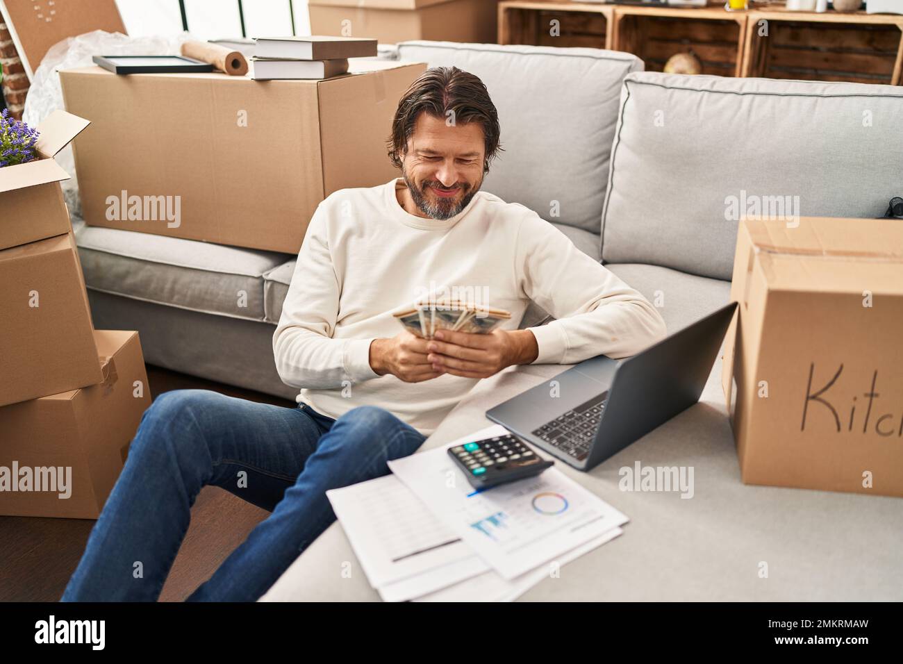 Middle age man using laptop counting denmark kroner banknotes at new ...