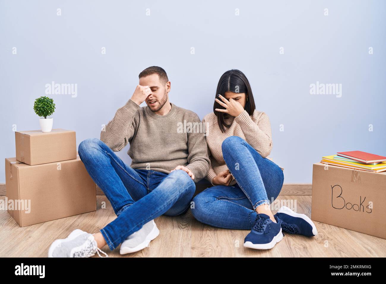 Young couple moving to a new home tired rubbing nose and eyes feeling ...