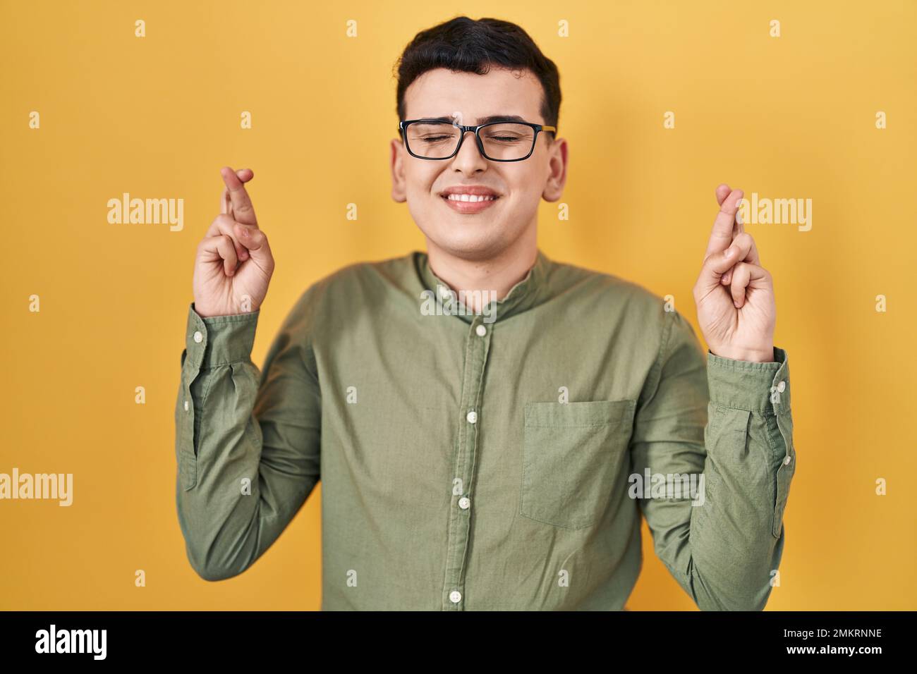 Non binary person standing over yellow background gesturing finger ...