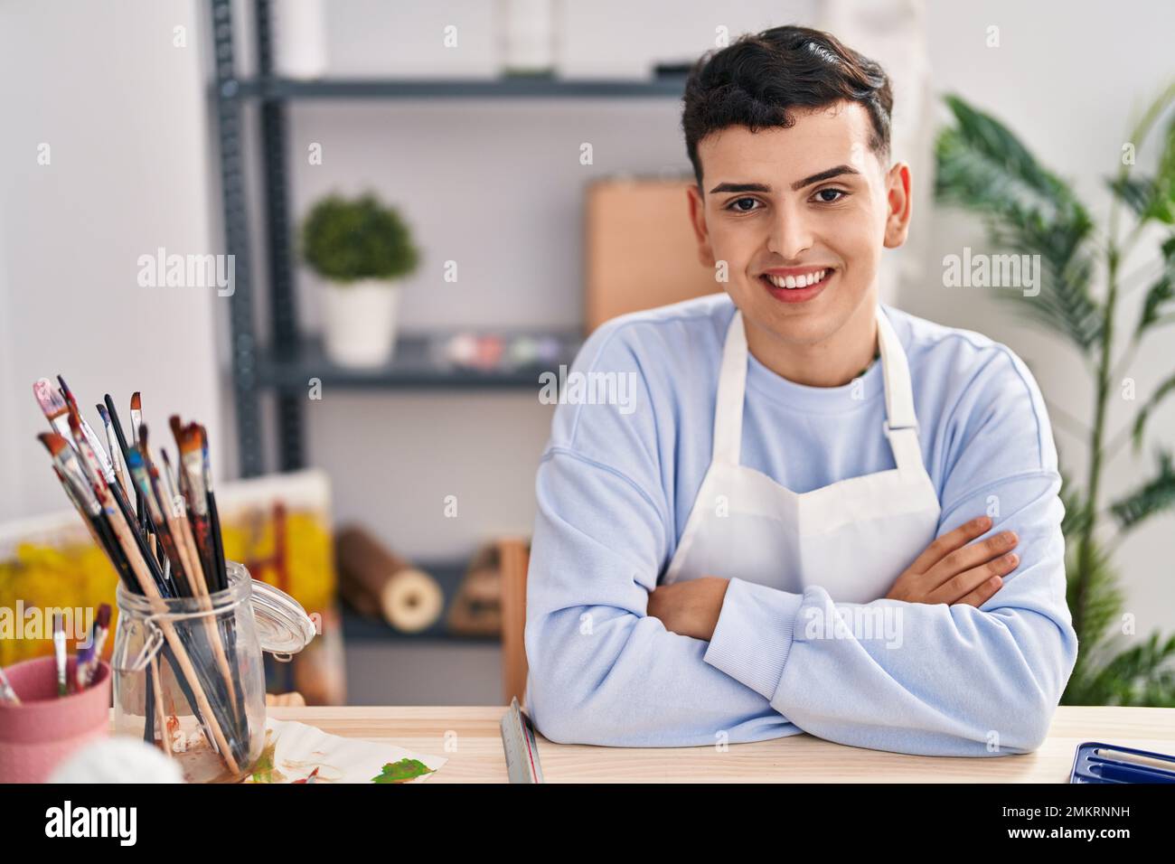 Young non binary man artist smiling confident sitting with arms crossed ...