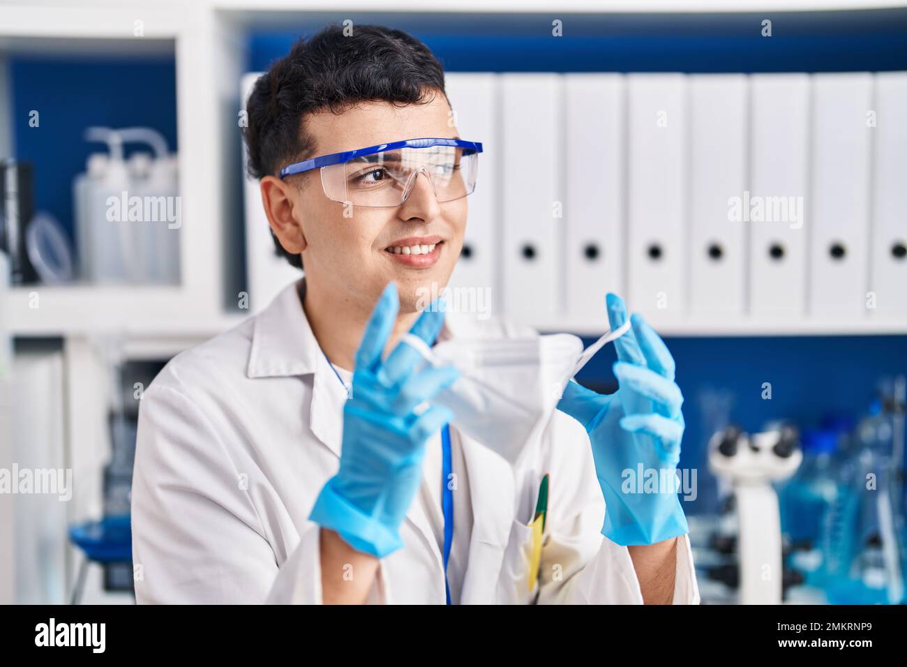 Young non binary man scientist smiling confident holding medical mask at laboratory Stock Photo ...