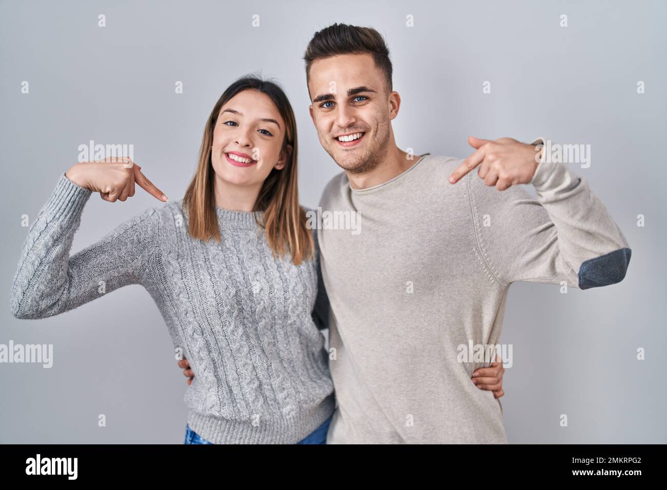 Young hispanic couple standing over white background looking confident ...