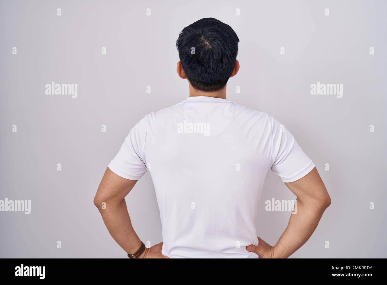 Young asian man standing over white background standing backwards ...