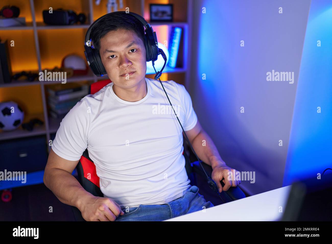 Young chinese man streamer sitting on table with serious expression at ...